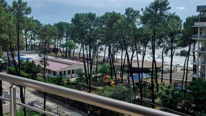 Vista costeira com praia, árvores e um edifício com telhado vermelho.