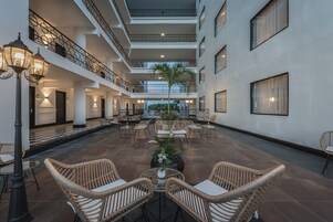 Um espaço amplo e interno com vários níveis, móveis de vime e uma planta central.