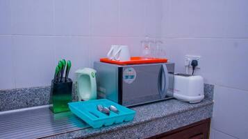 Cozinha equipada com micro-ondas, torradeira e bandeja com utensílios.