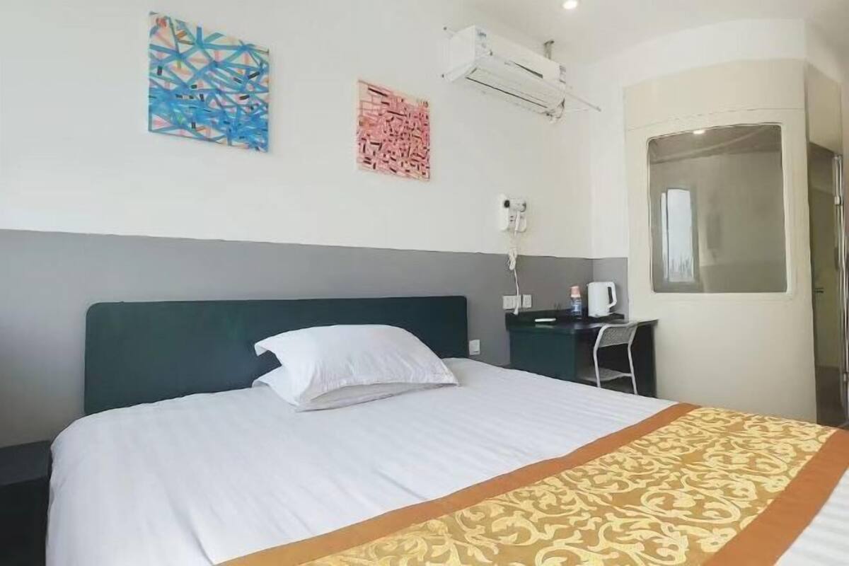 Quarto de hotel com cama, escrivaninha e área de chuveiro.