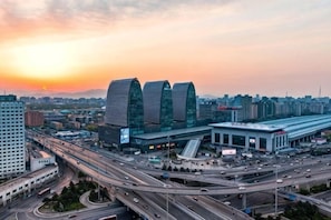Paisagem urbana com edifícios modernos, uma autoestrada e uma estação de trem.