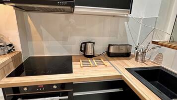 Cozinha moderna com fogão preto, cafeteira e pia.