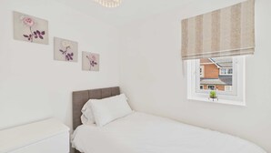 Quarto com uma cama, penteadeira e três quadros florais na parede.
