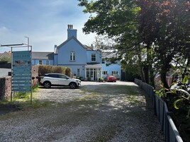 Uma casa azul com entrada de automóveis em cascalho e uma placa.