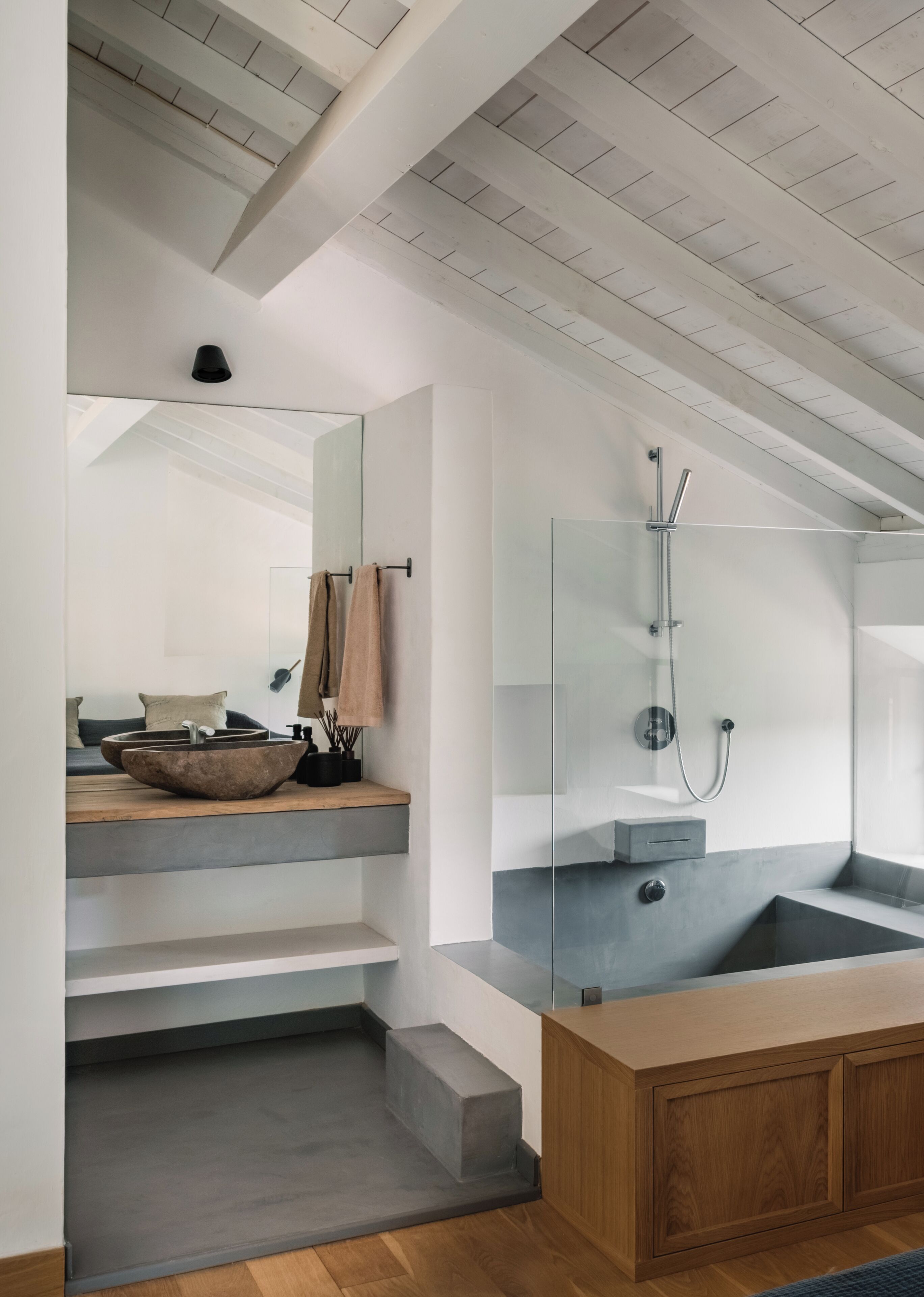 Uma casa de banho moderna com uma banheira grande, cabine de duche com parede de vidro e toucador de madeira.