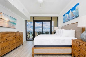 Quarto com cama grande, cómoda de madeira e pintura de veleiros.