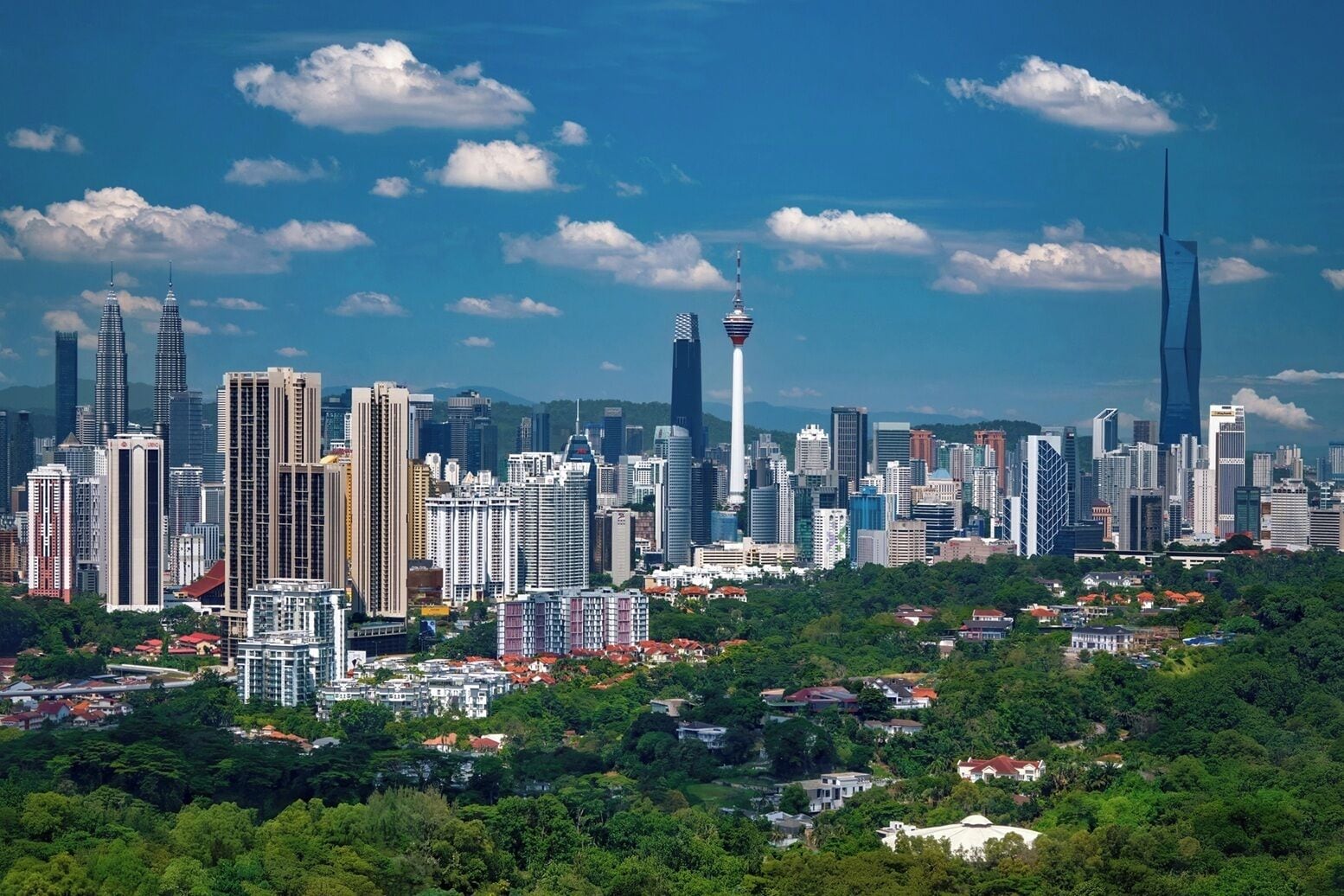 Paisagem urbana com arranha-céus modernos, uma torre imponente e uma combinação de edifícios residenciais e comerciais.