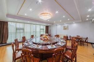 Sala de conferências com mesa redonda, cadeiras e um candelabro.