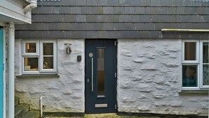 Uma casa com porta azul escura, paredes externas brancas e telhado cinza.