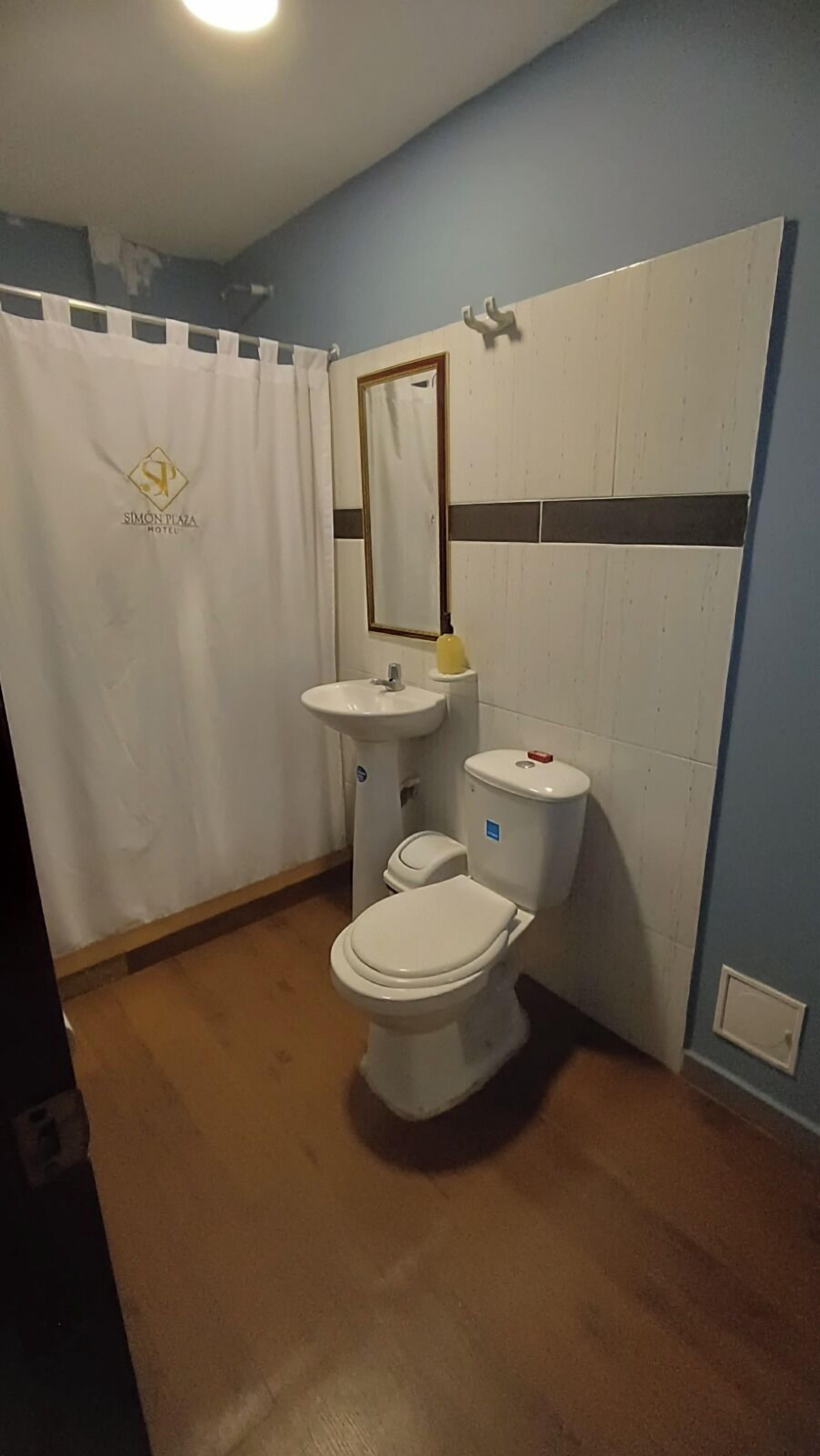 Casa de banho com sanita branca, lavatório e espelho.