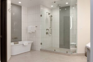 Uma casa de banho moderna com chuveiro envolto em vidro, uma banheira independente e uma sanita.