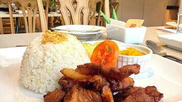 Mesa de jantar com arroz branco, carne frita e uma porção de legumes.