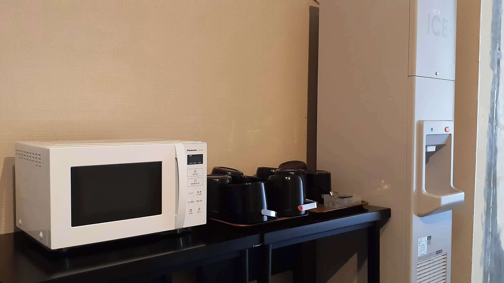 Um micro-ondas branco sobre uma bancada preta, com dispensador de água e máquina de café.