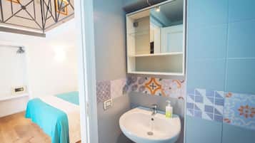 Quarto quádruplo conforto, vista para o pátio | Banheiro | Chuveiro, chuveiro com efeito de chuva, produtos de toalete grátis
