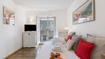 Quarto moderno com uma cama, uma televisão, um sofá e um quadro.