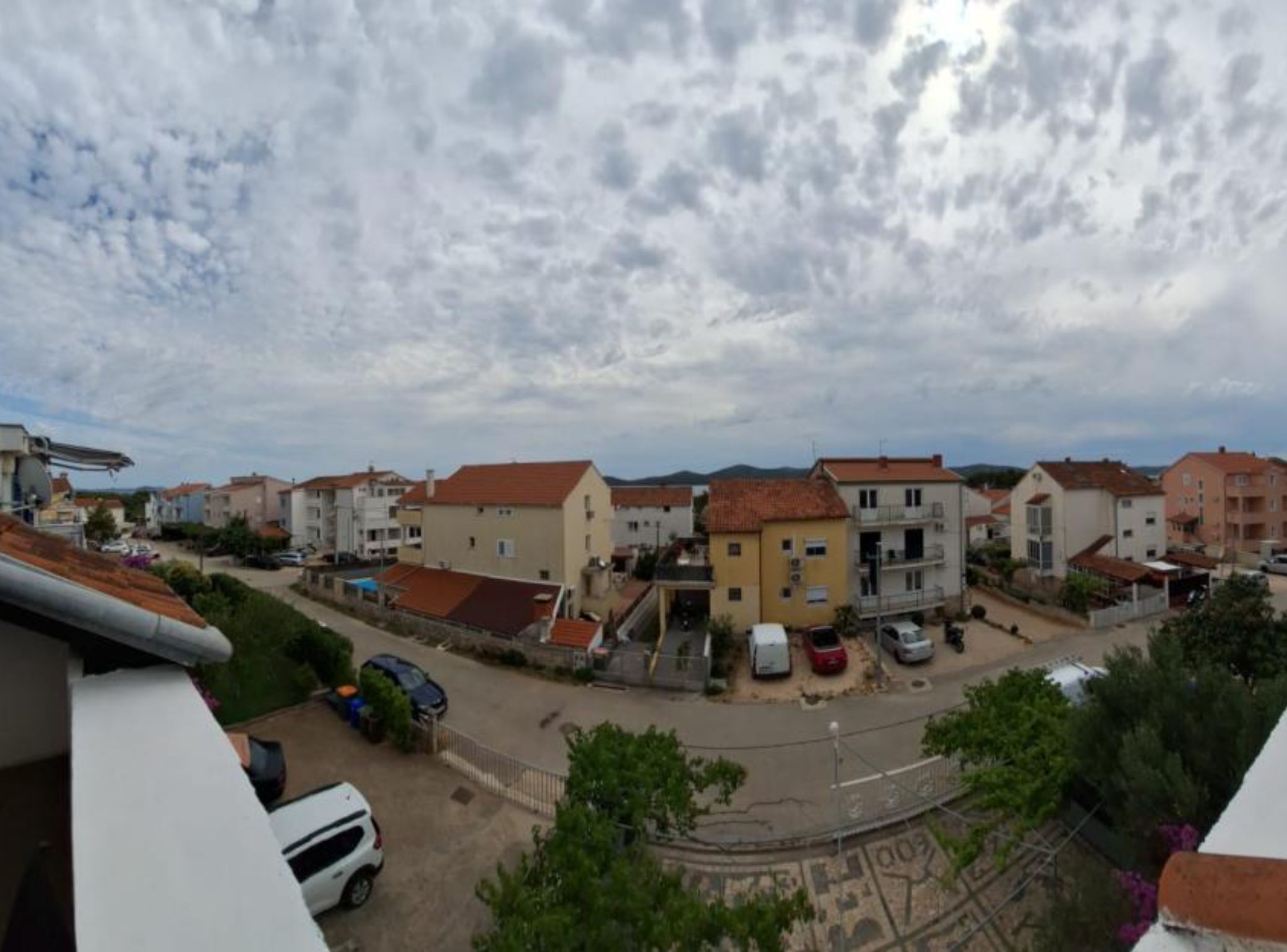 Zona residencial com vários edifícios de dois andares, um estacionamento e uma rua.