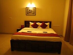 Uma cama bem arrumada com um cobertor vermelho, dois travesseiros e um controle remoto na cama.