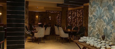 Uma sala de jantar com uma mesa comprida posta para várias pessoas, rodeada de cadeiras.