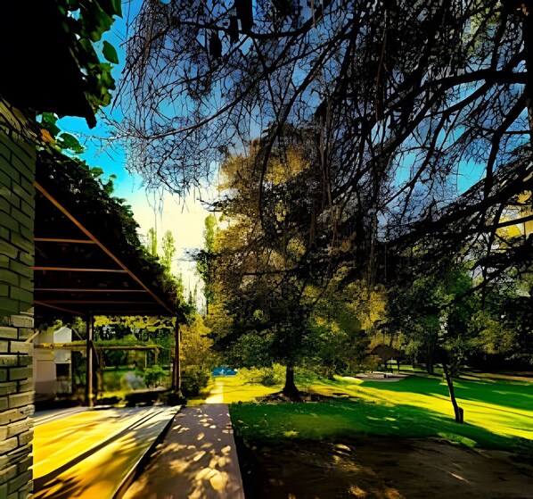 Uma trilha serpenteia por um parque com árvores e um edifício à esquerda.