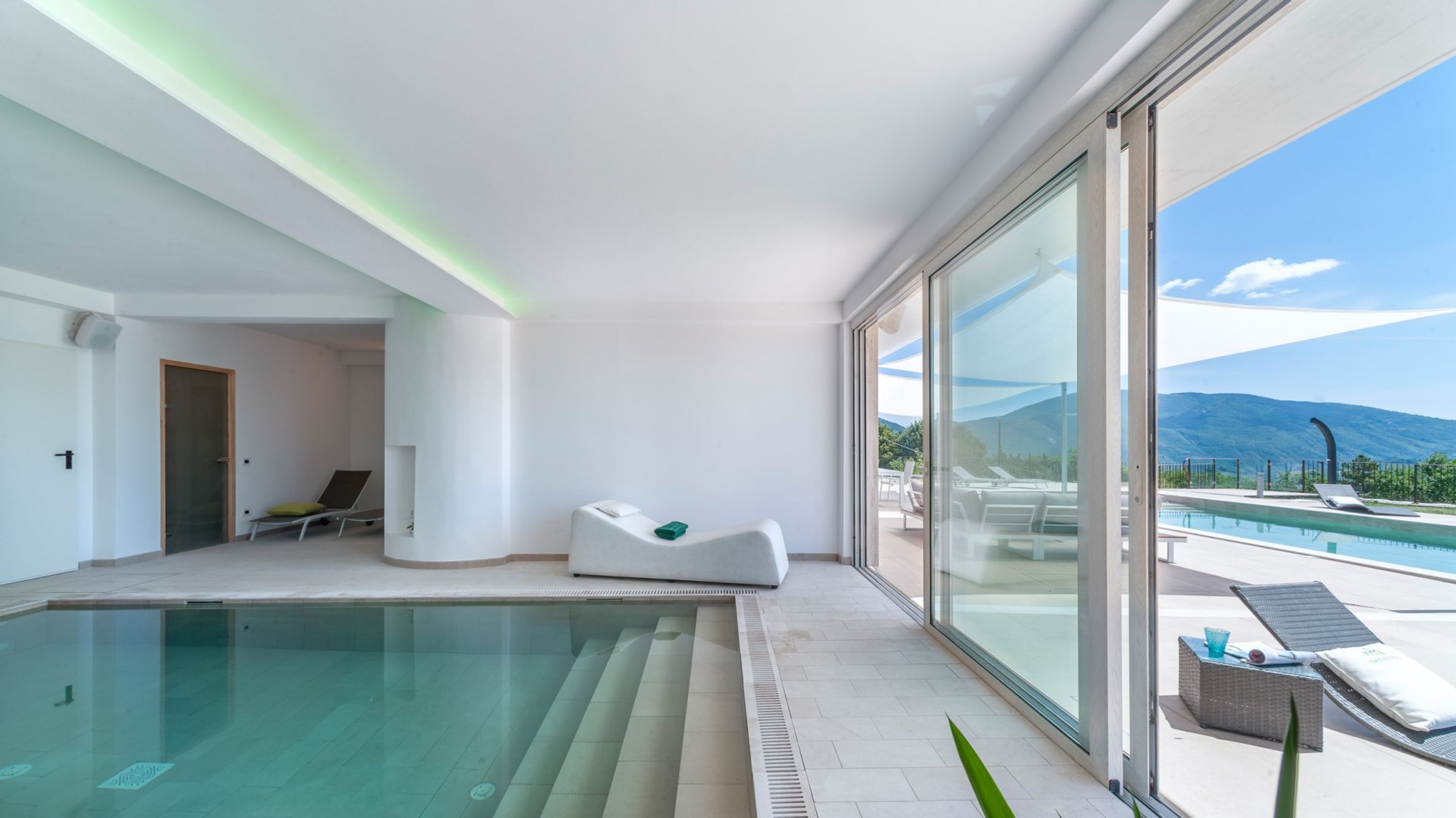 Área de piscina interior moderna com vista clara para as montanhas.