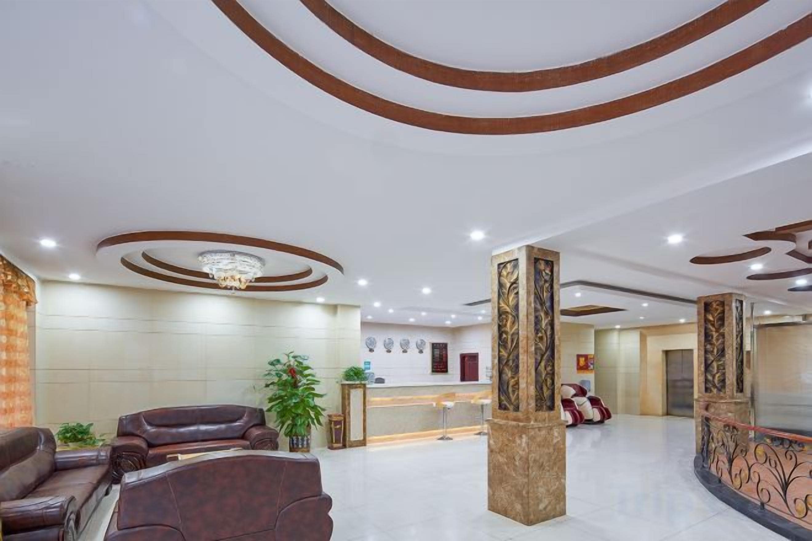 Um saguão de hotel com balcão de recepção, área de estar e teto decorativo.