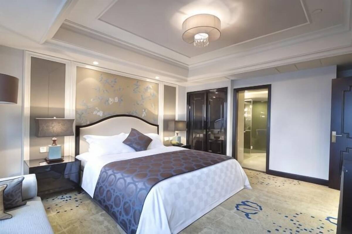 Quarto de hotel moderno com cama grande, mesas de cabeceira, escrivaninha e closet espaçoso.