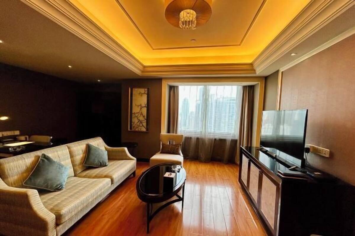 Uma sala de estar moderna com um sofá, poltrona, mesa de centro e uma TV de tela plana.