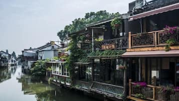 Um edifício tradicional com vários níveis, varandas com plantas e um canal em frente.