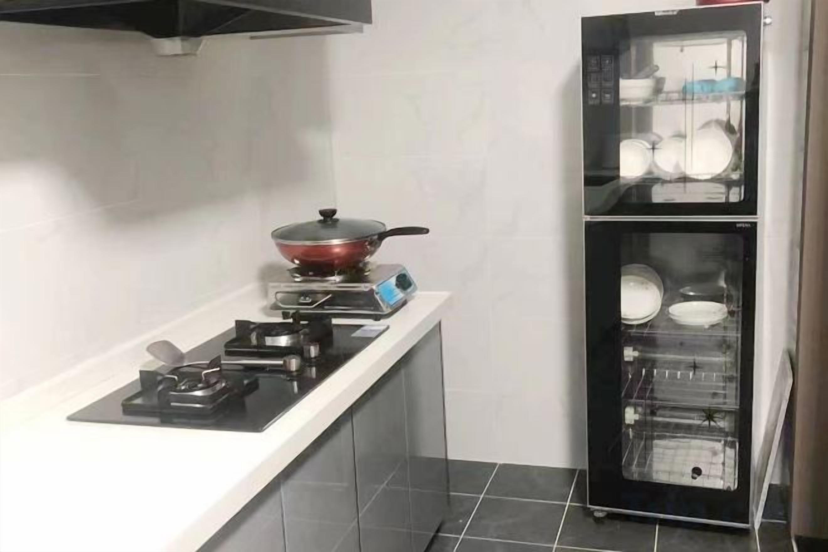 Cozinha equipada com fogão a gás, wok e frigorífico de duas portas.