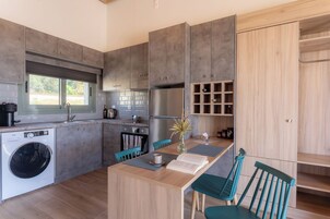 Uma cozinha moderna com armários cinza, máquina de lavar embutida e área de refeições com mesa de madeira e cadeiras cor turquesa.