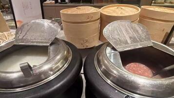 Disposição de buffet com vários recipientes de comida e utensílios de servir.