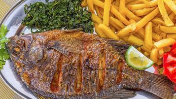 Um prato com peixe grelhado, batatas fritas e vegetais.