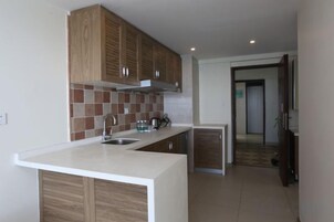 Cozinha com armários de madeira, bancada branca e painel de azulejos.