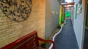 Um beco estreito com um banco, arte decorativa na parede e um caminho iluminado em verde.