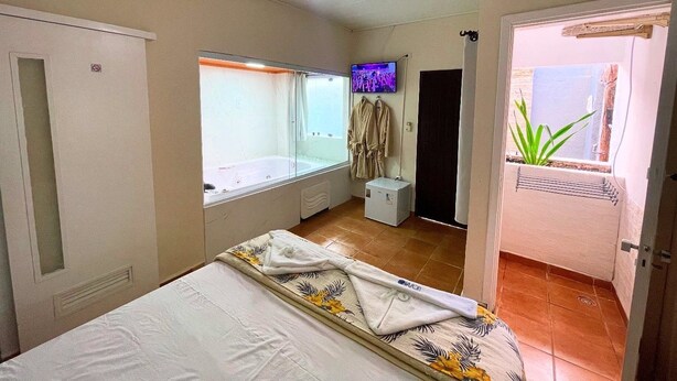 Quarto com cama, janela com vista, ventoinha no teto e televisão.