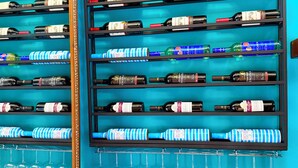 Prateleira de vinhos com várias garrafas e copos.