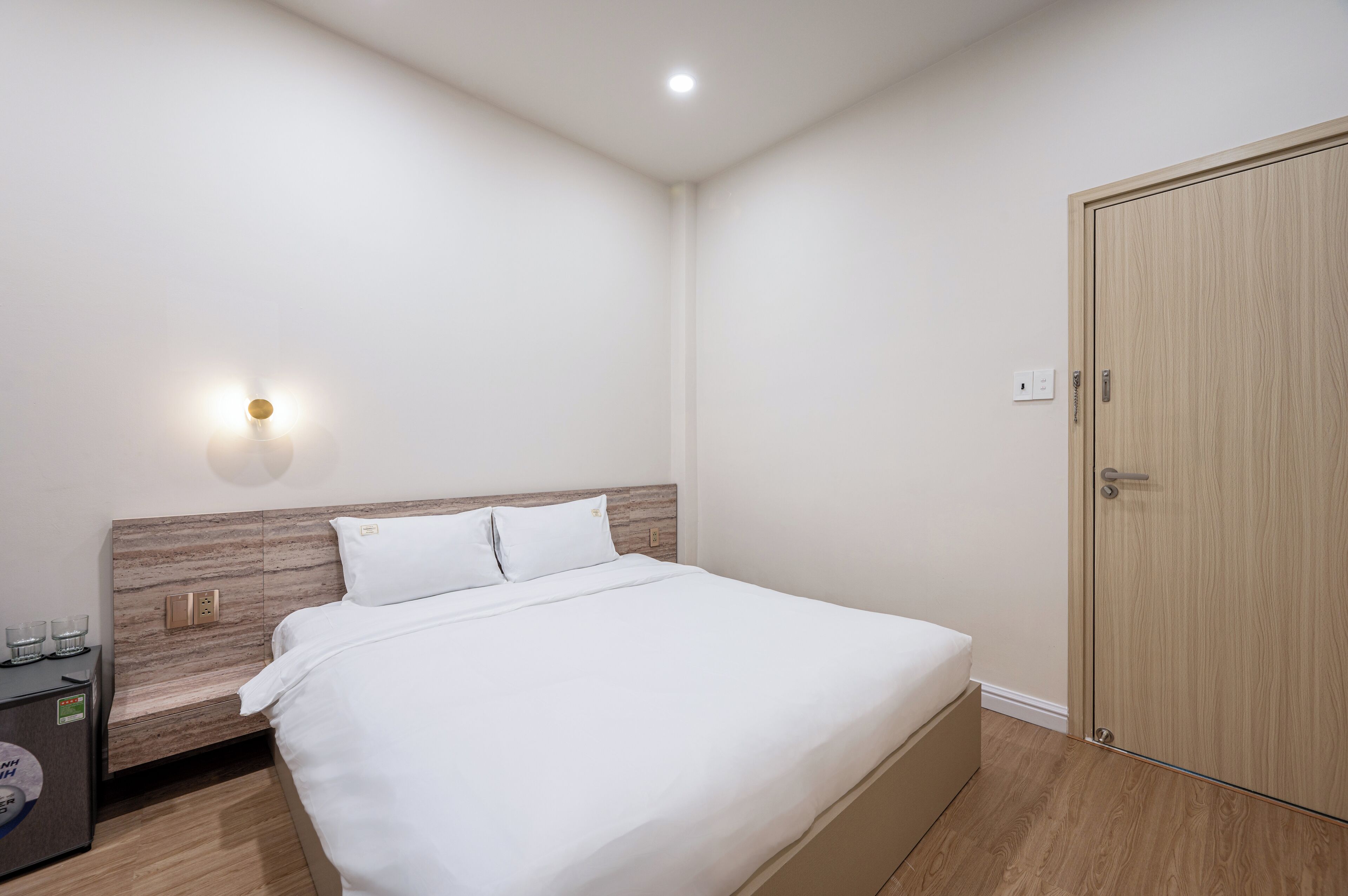 Quarto de hotel com cama, mesa de cabeceira e guarda-roupa.