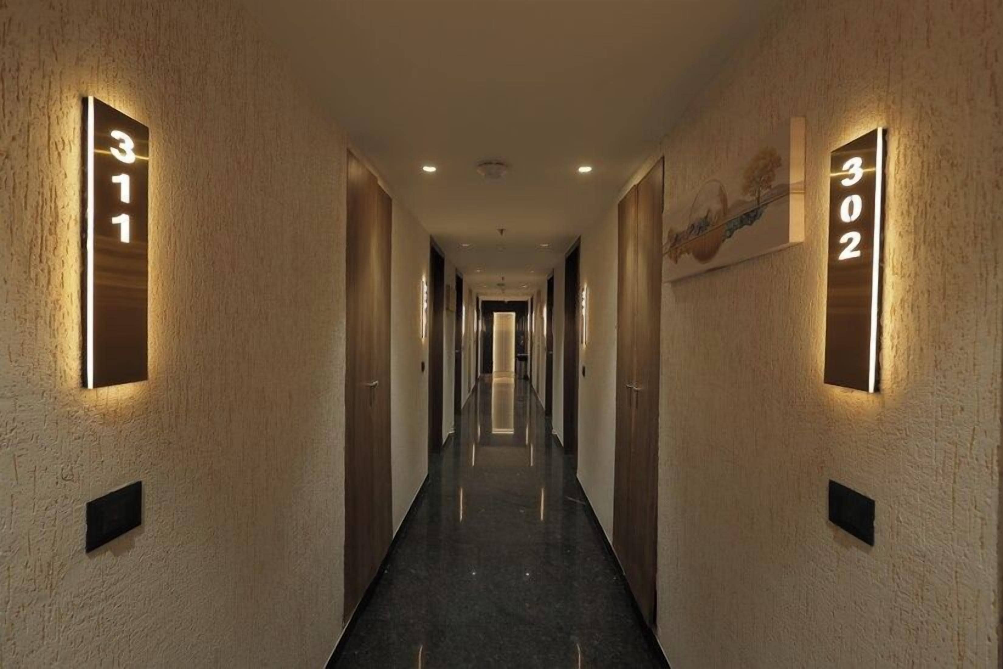 Corredor com números de quartos iluminados, 311 e 302, nas paredes.