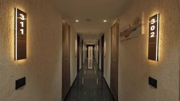 Corredor com números de quartos iluminados, 311 e 302, nas paredes.