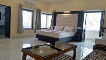Quarto de hotel com cama, mesa de vidro e vista para o exterior.