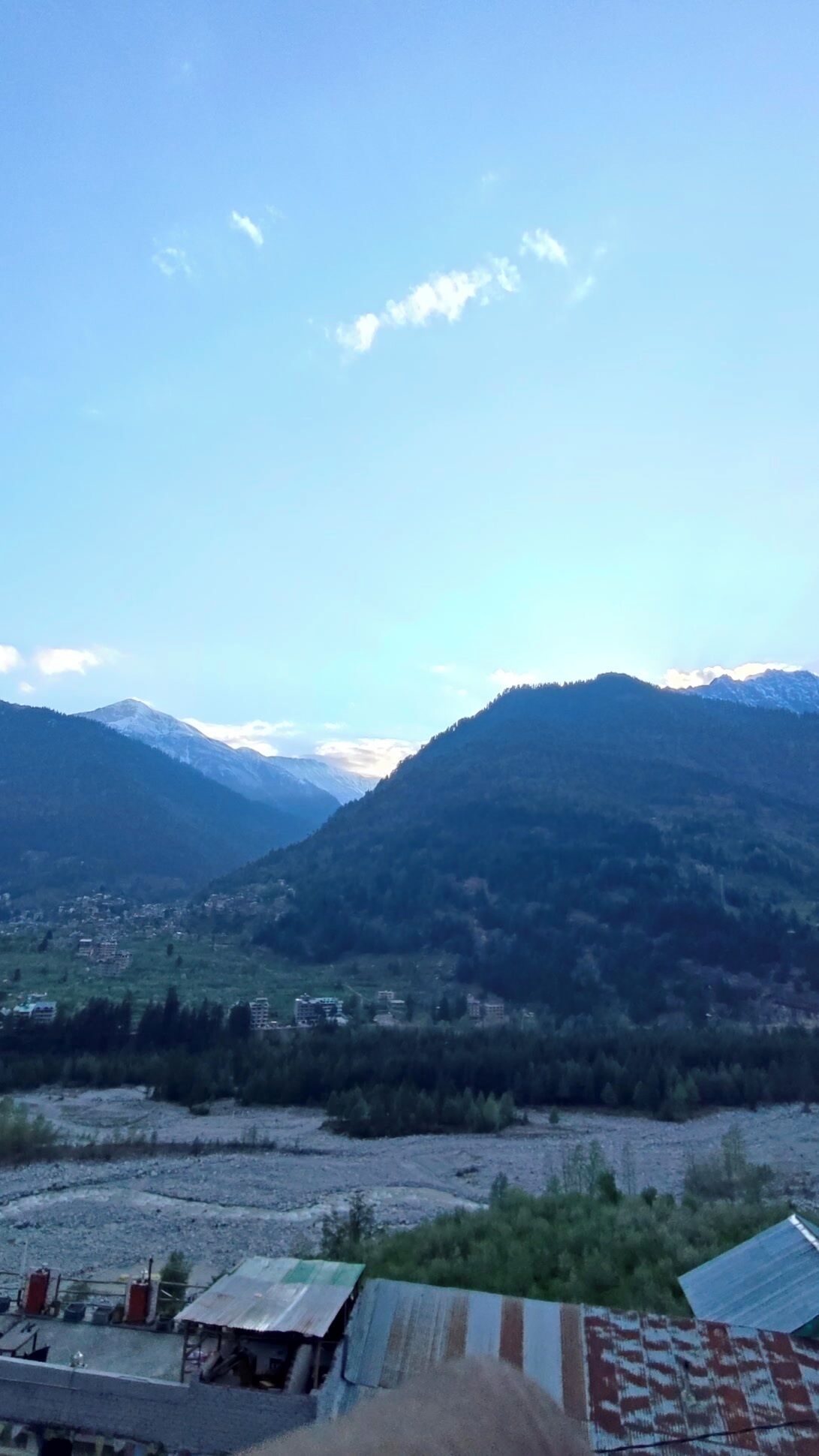 Paisagem montanhosa com um vale abaixo, apresentando um pequeno povoado com edifícios e algumas construções.