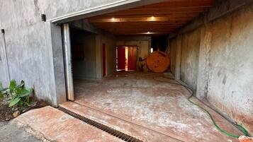 Um edifício inacabado com fachada de concreto, teto de madeira e porta de metal.