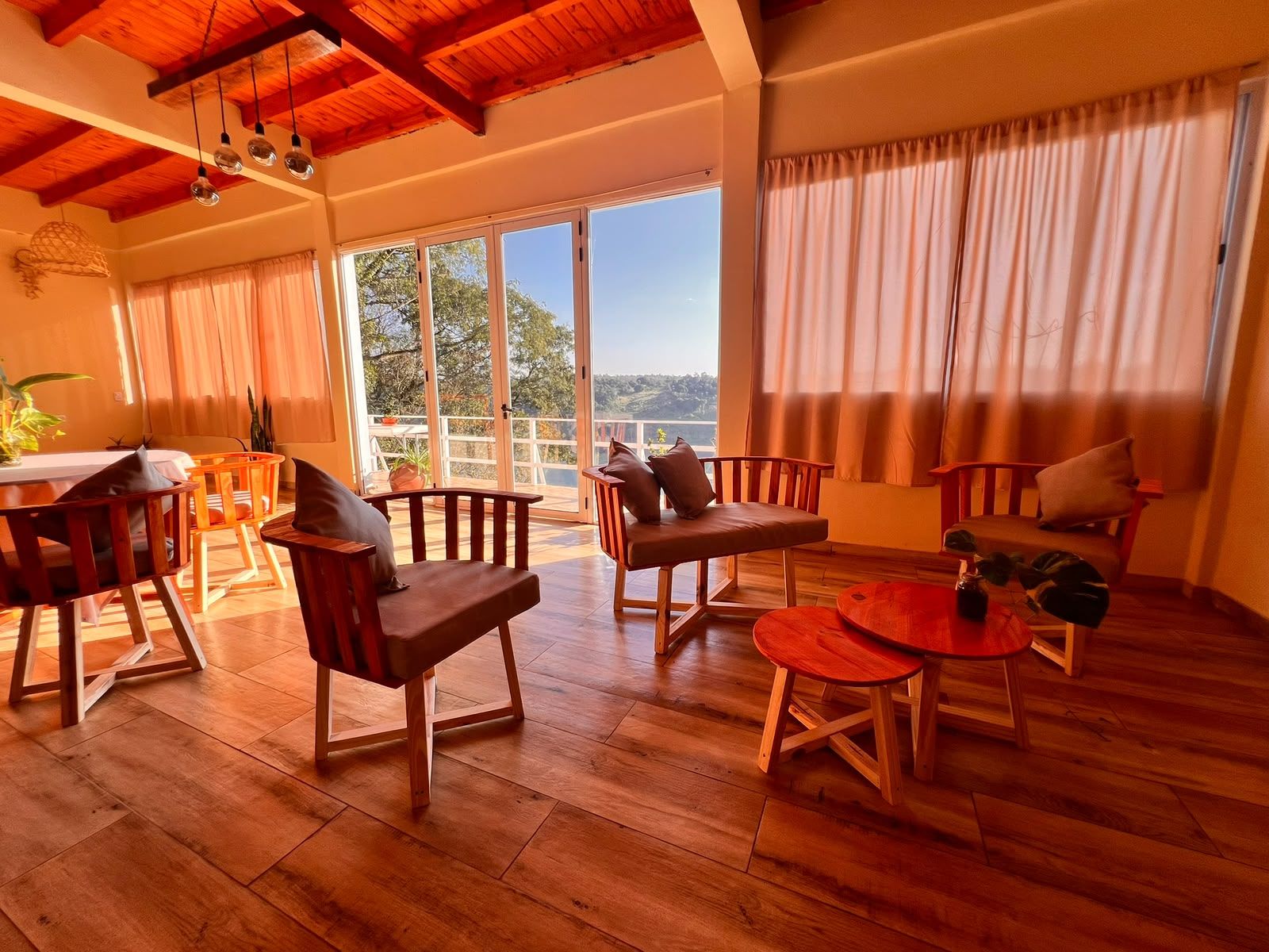 Um quarto amplo com piso de madeira, área de jantar com mesa e cadeiras, e grandes janelas com vista para o exterior.