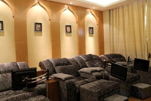 Sala de cinema com várias fileiras de assentos, uma tela e sistema de som.