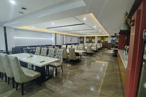 Um restaurante com várias mesas e cadeiras, um balcão com menu e chão em azulejos.