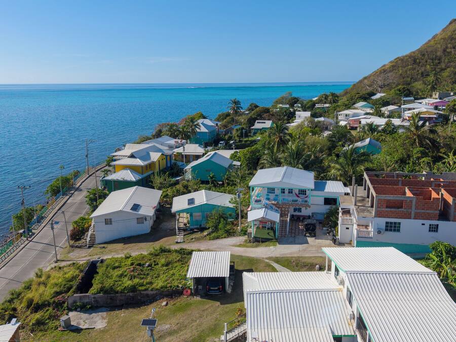 Uma vila costeira com casas, uma estrada e vista para o mar.
