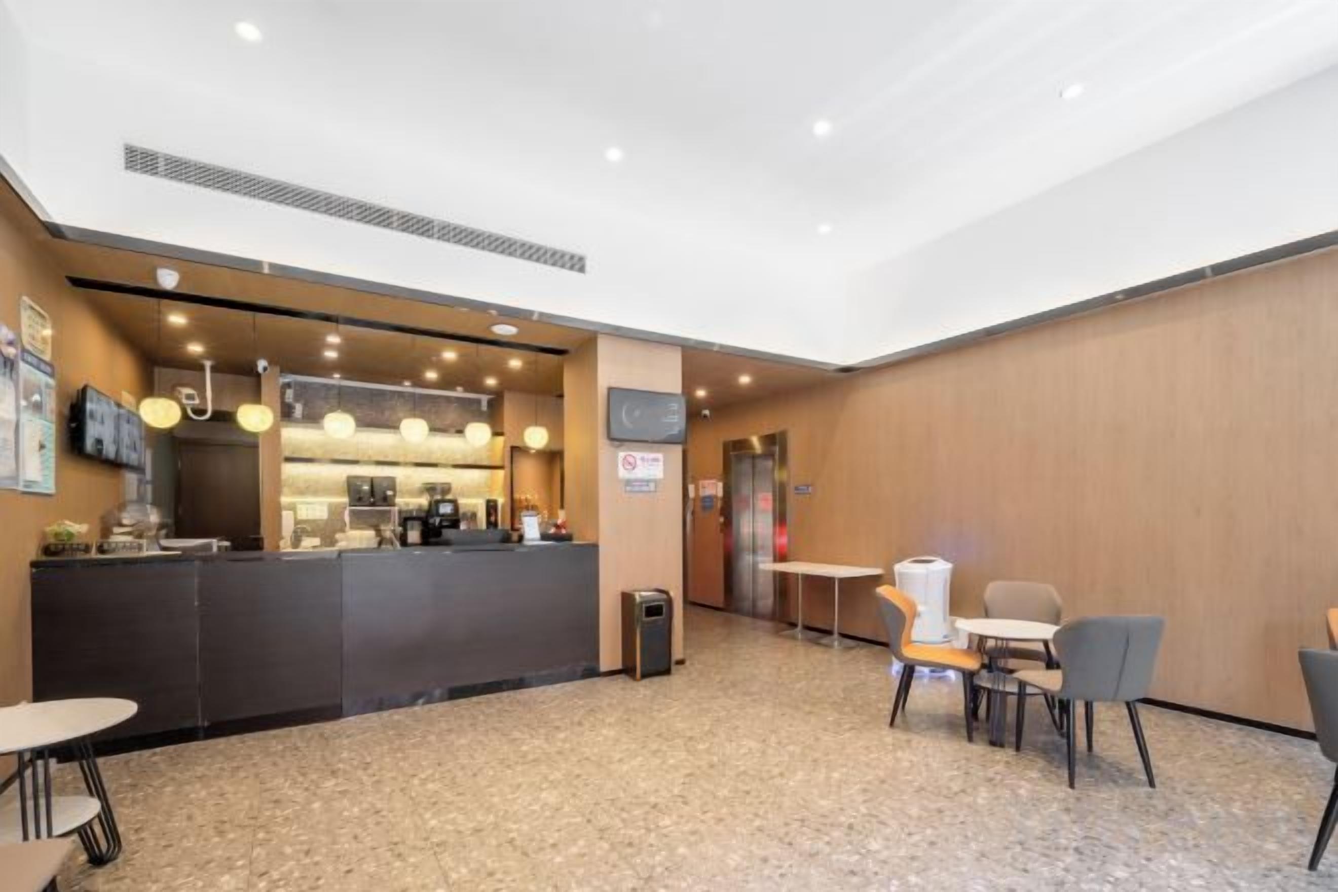 Um saguão de hotel com balcão de recepção, área de estar e lixeira.