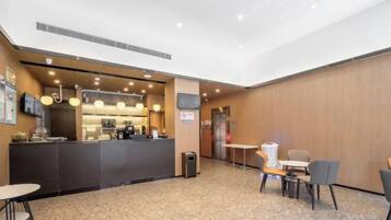 Um saguão de hotel com balcão de recepção, área de estar e lixeira.
