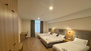 Quarto de hotel com duas camas, uma escrivaninha e um guarda-roupa.