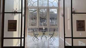 Uma estufa com teto de vidro, duas cadeiras e uma mesa no centro.